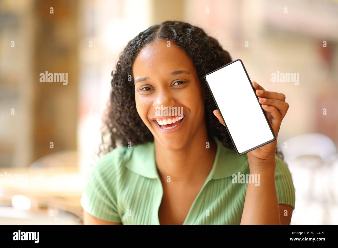 Happy Black Woman Laughing Showing Blank Phone Screen In A Bar Terrace