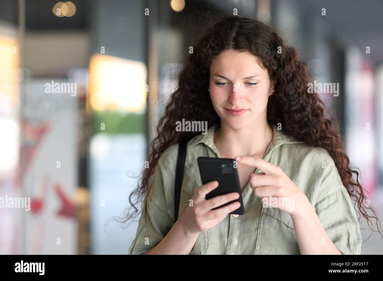 Woman checking phone walking in the street Stock Photo - Alamy