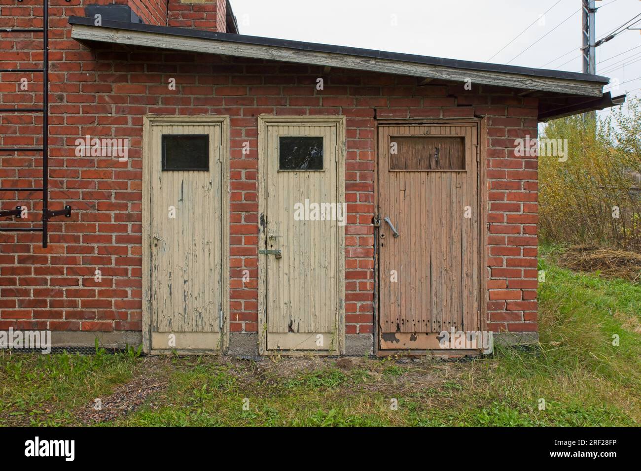 Three wood doors on a red brick building Stock Photo - Alamy