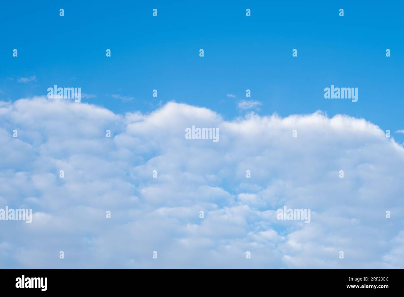 Dense white horizontal clouds in half the frame and blue sky. A ...