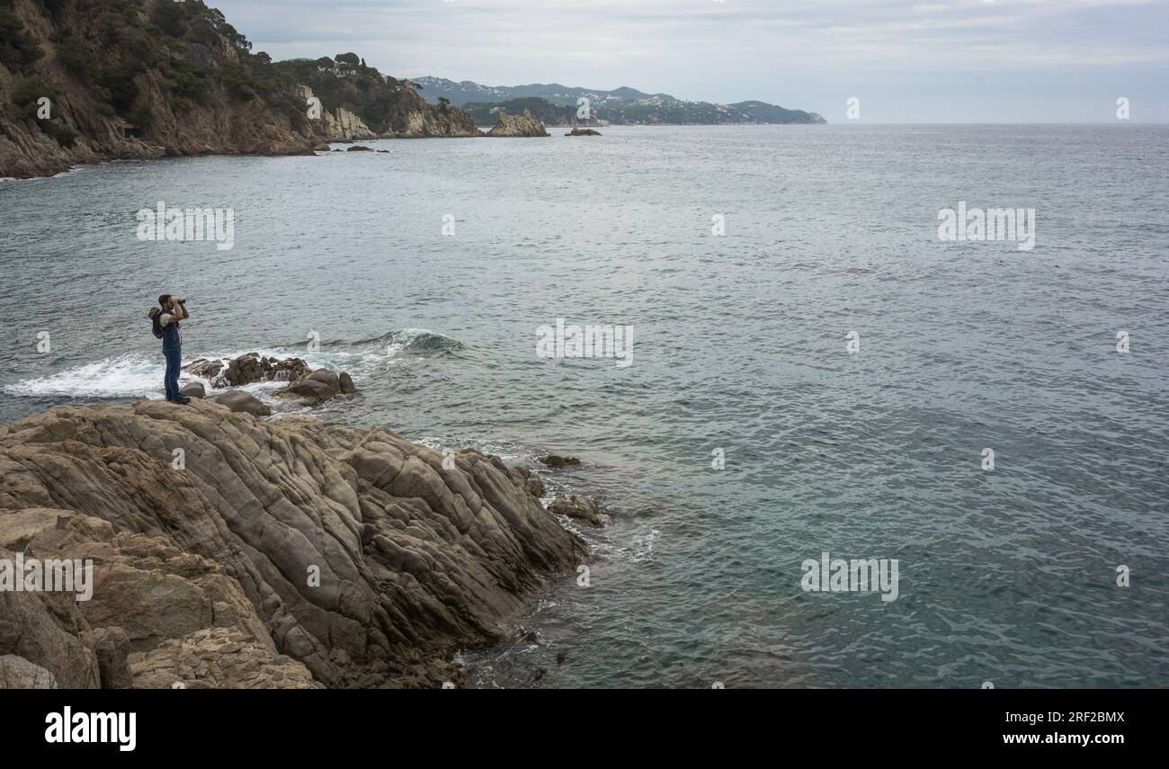 Adventurous man with photo camera and binoculars exploring a roc Stock ...