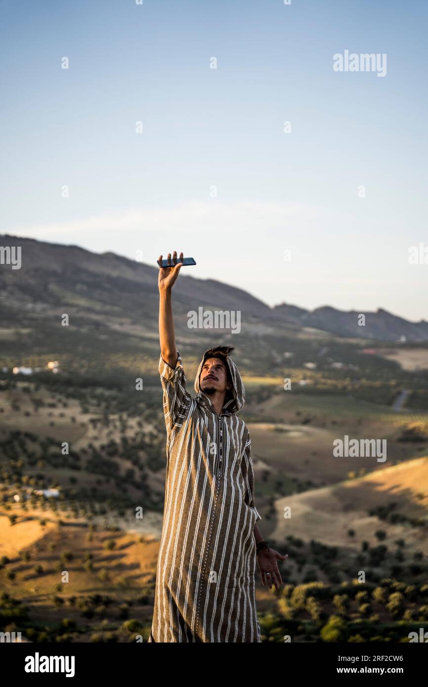 Moroccan man in typical Arabic attire lifting mobile phone up Stock ...