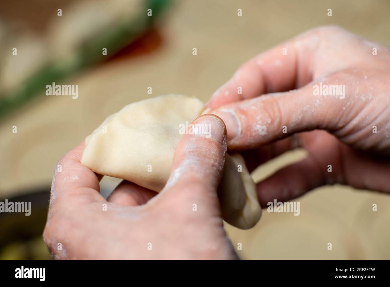 Sculpting dumplings close-up. Women's hands make dumplings stuffed with ...