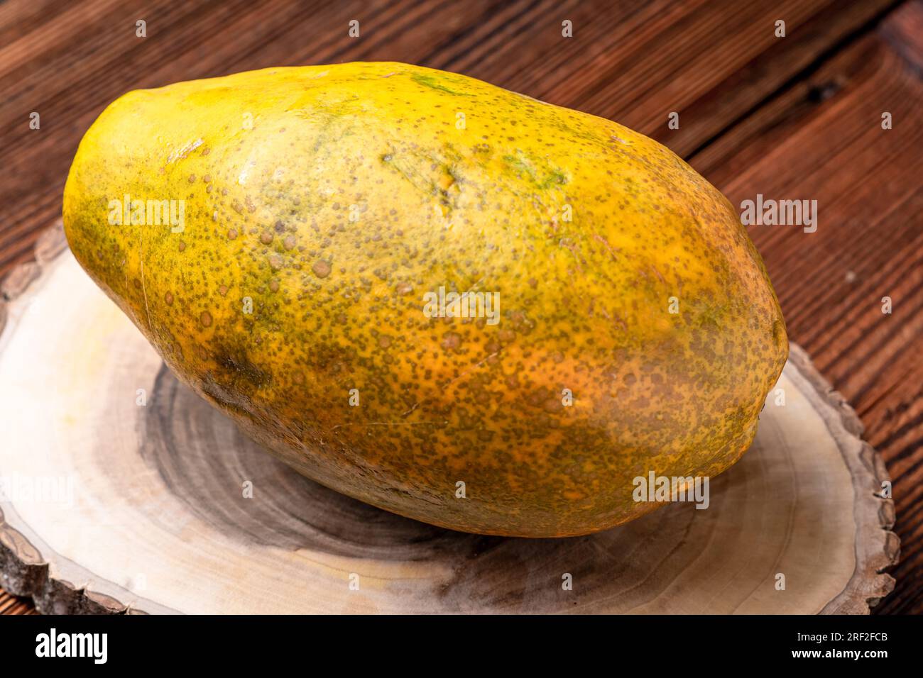 whole papaya on a wooden background. An imperfect-looking fruit with an ...