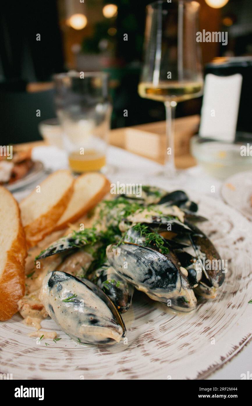 Mussels in cream sauce with bread and wine. Seafood close up. Fish dish ...