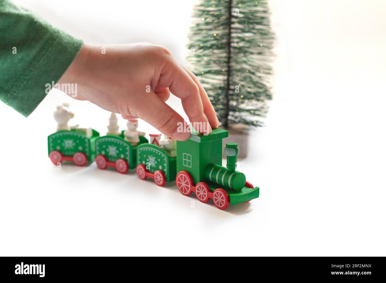 A little boy plays with a toy Christmas train and a figurine of a ...