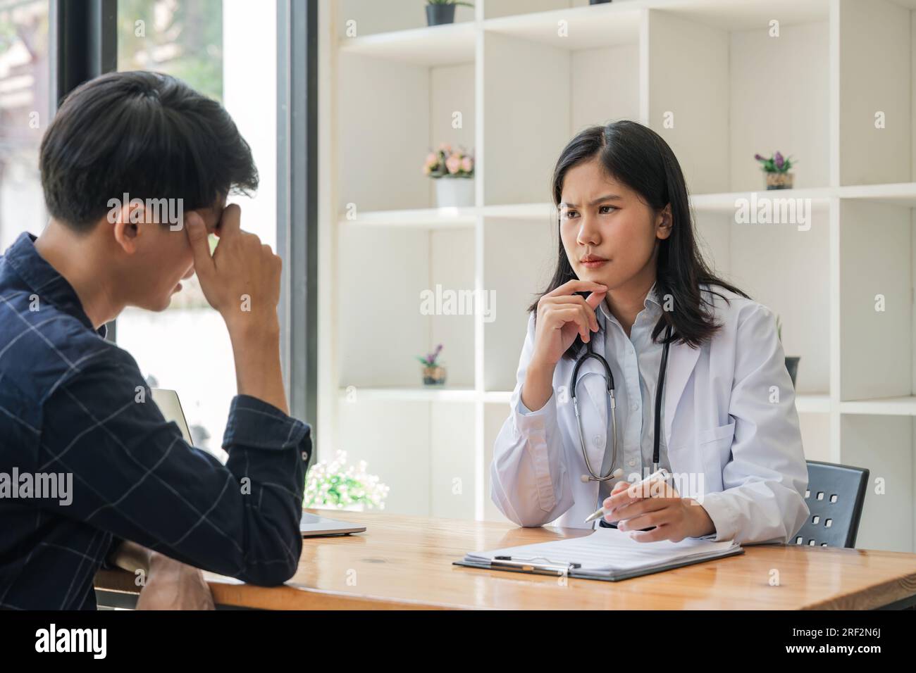 Young asian woman doctor consulting asian worried patient patient on ...