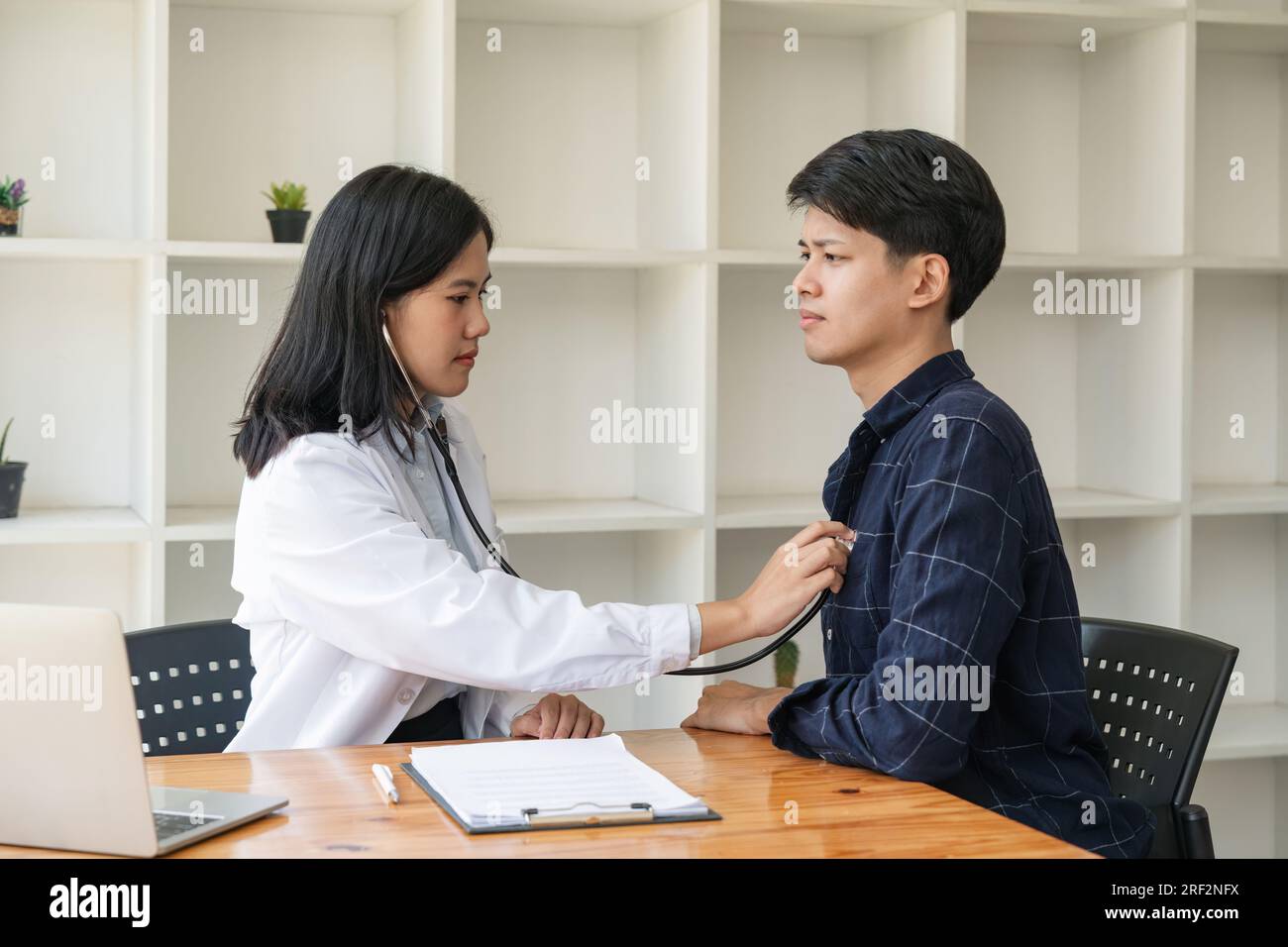 Asian man patient are checked up his health while a woman doctor use a ...