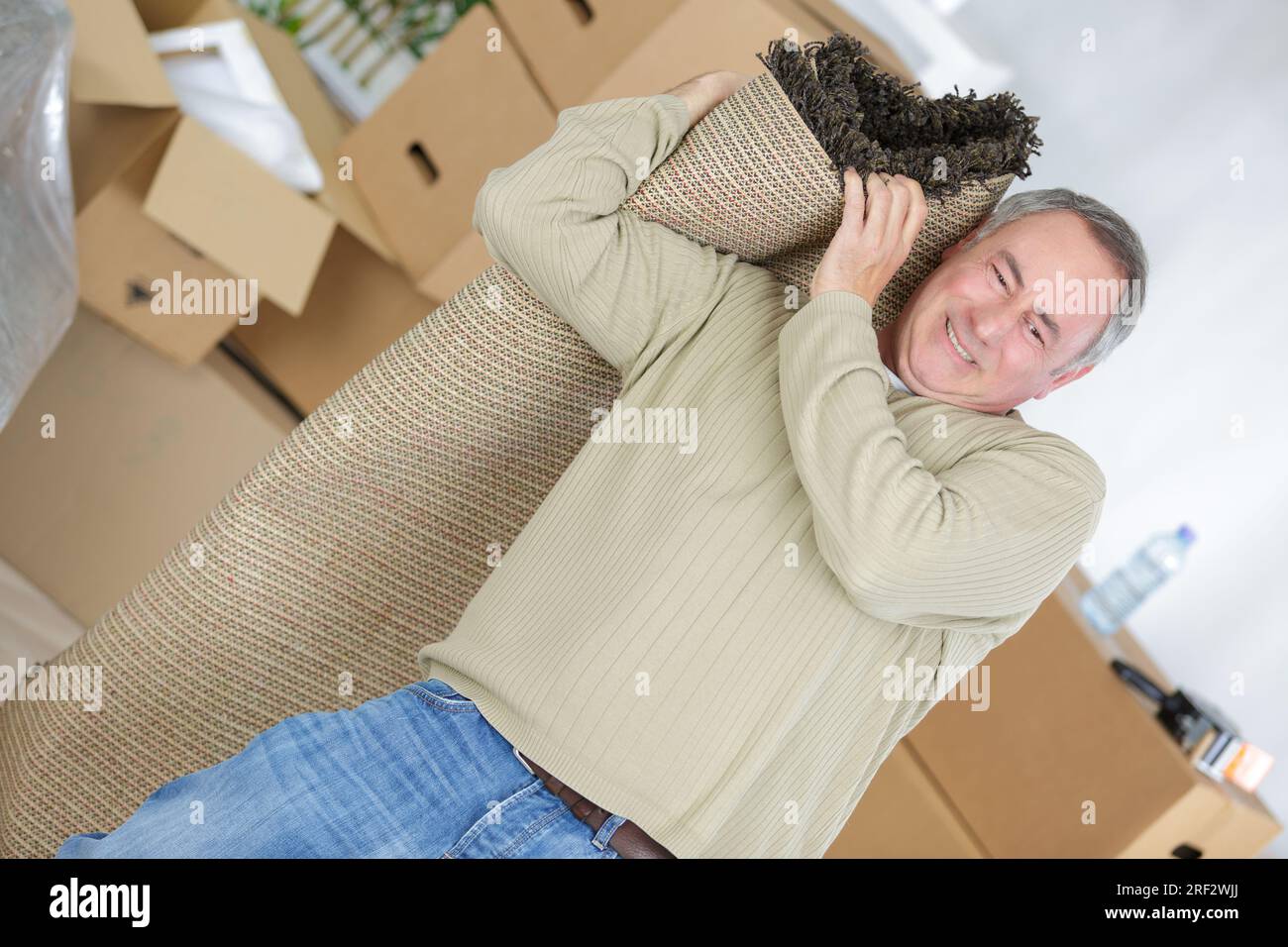 man struggling to carry rug on his shoulder Stock Photo - Alamy