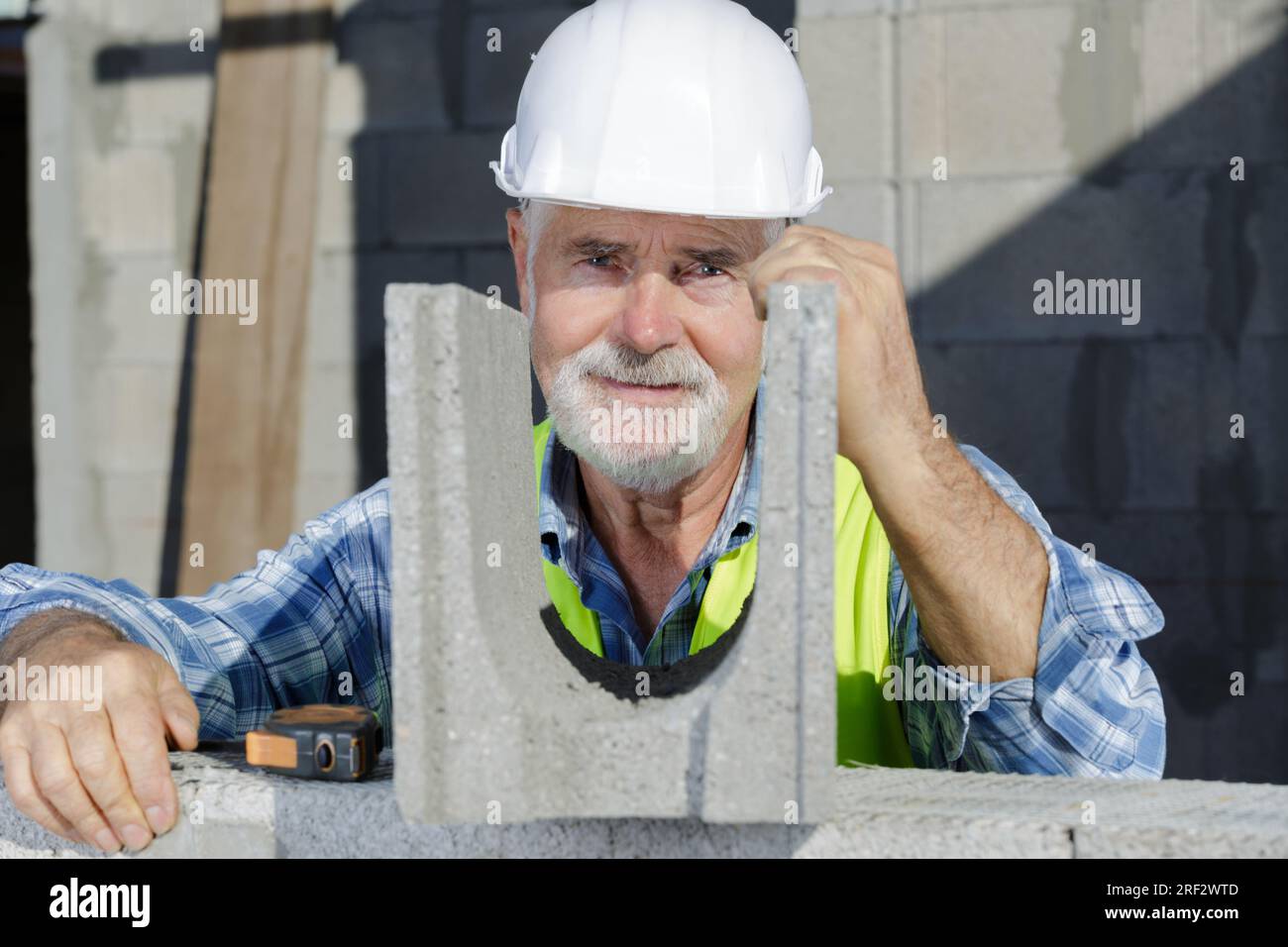 senior builder holds cement block Stock Photo - Alamy