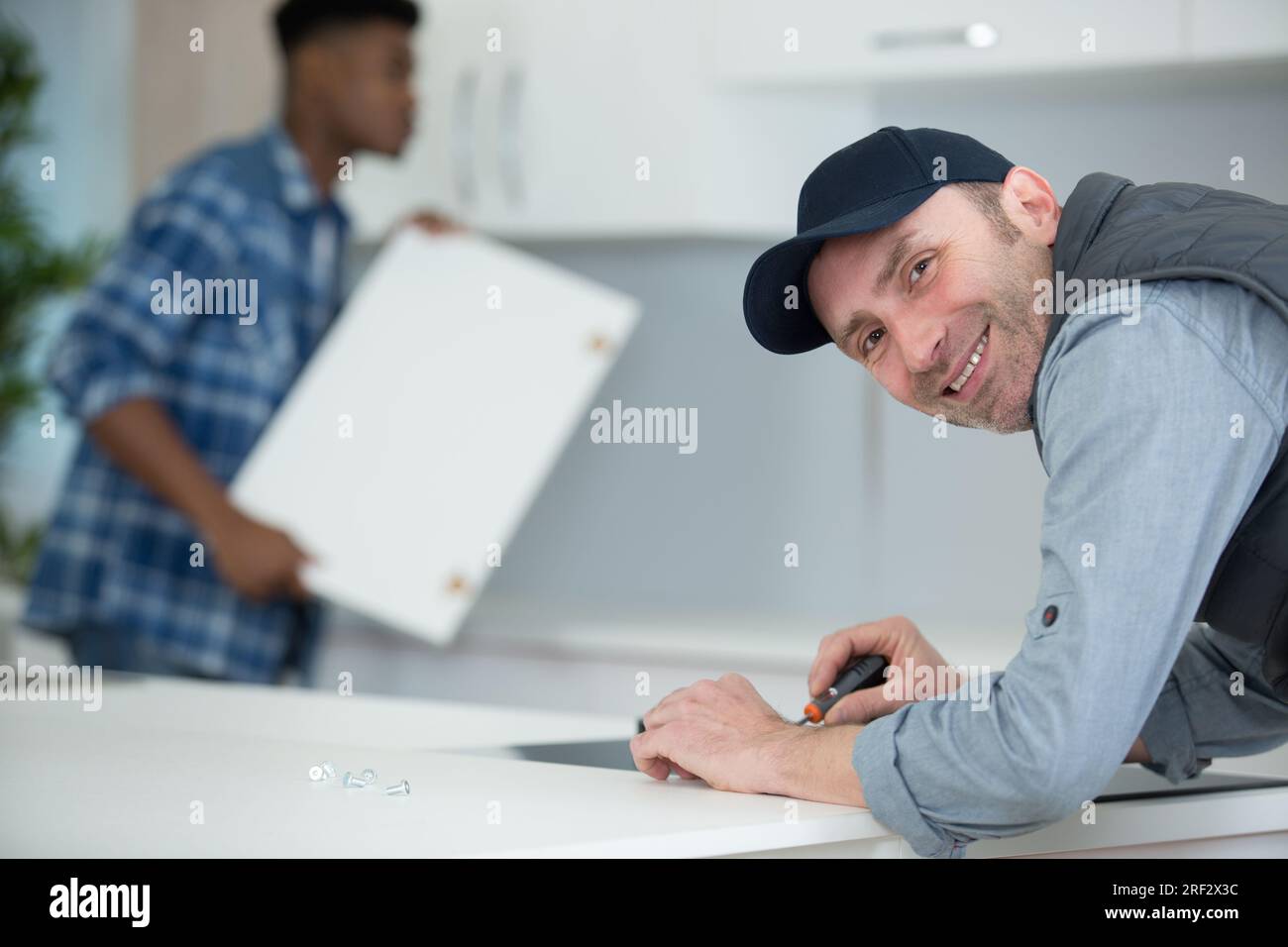 team of men installing a kitchen Stock Photo - Alamy