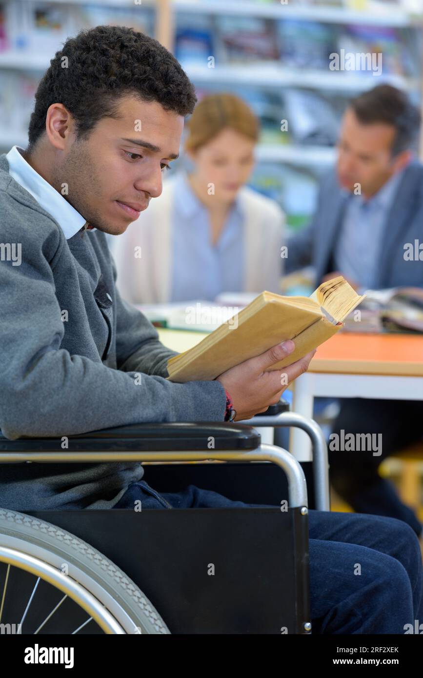 student on a wheelchair reading a book Stock Photo - Alamy