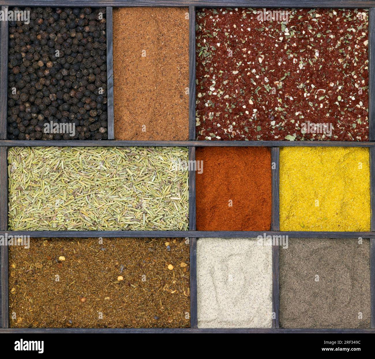 lots of various different spices in a framed dark wooden box seen from ...
