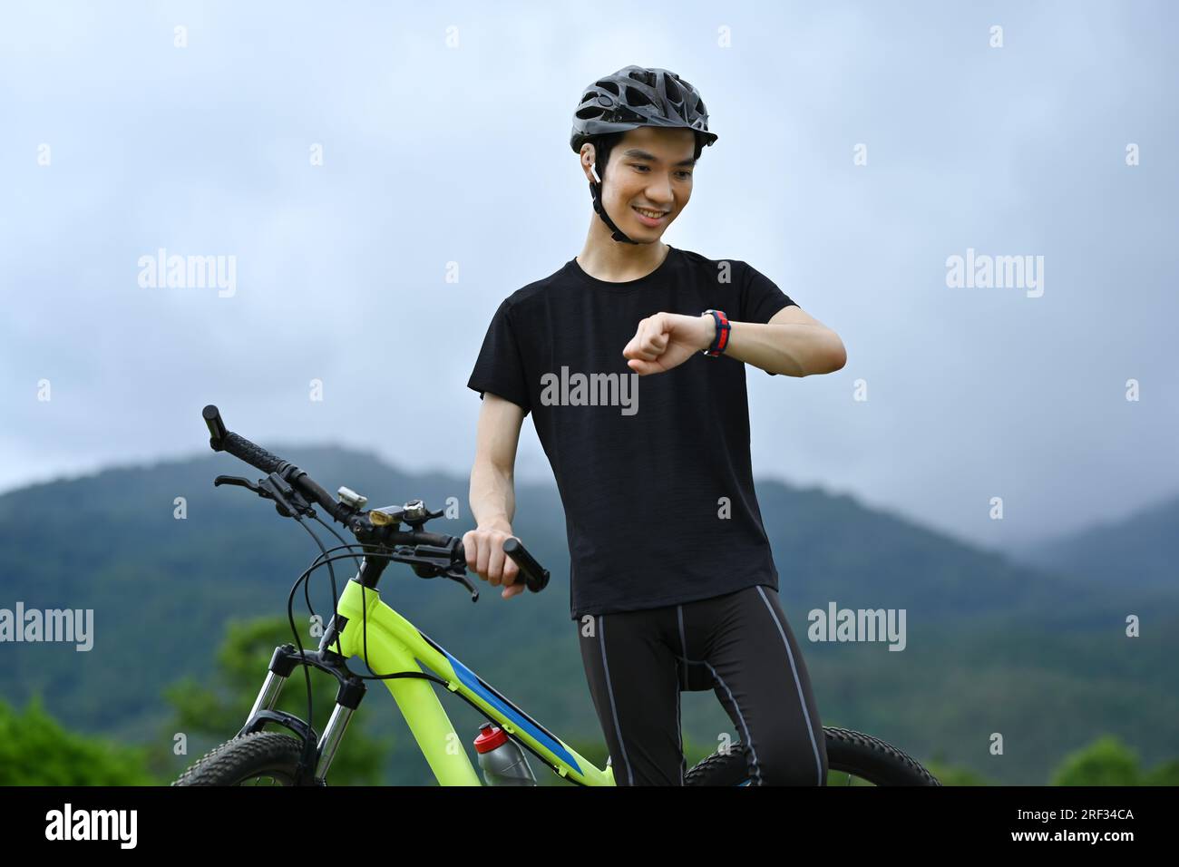 Satisfied man taking break from riding bicycle and checking sport ...