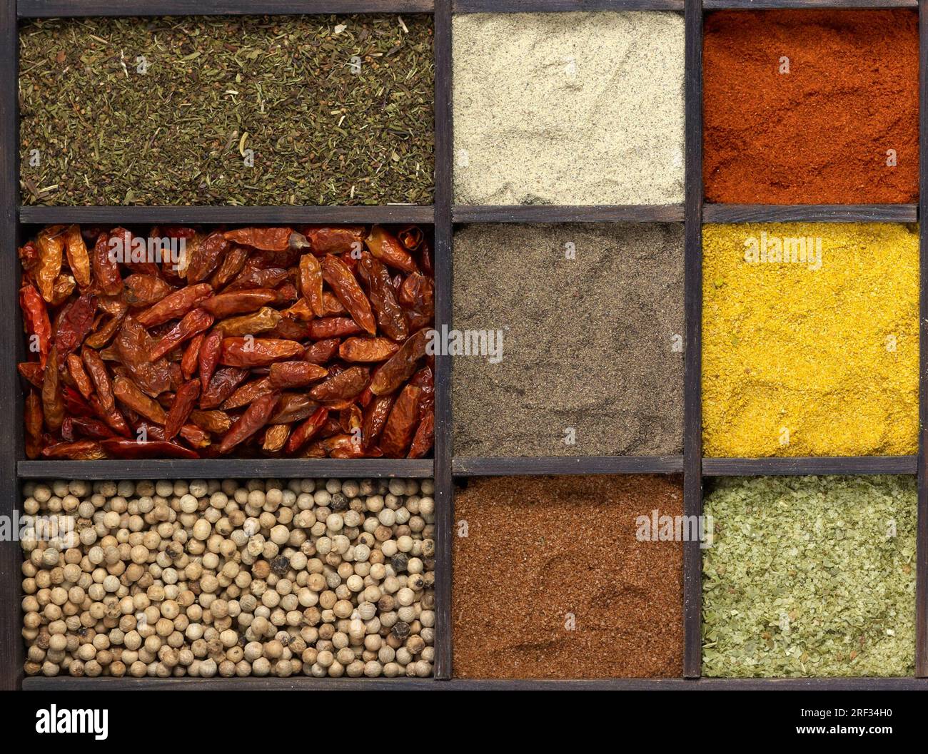 lots of various different spices in a framed dark wooden box seen from ...