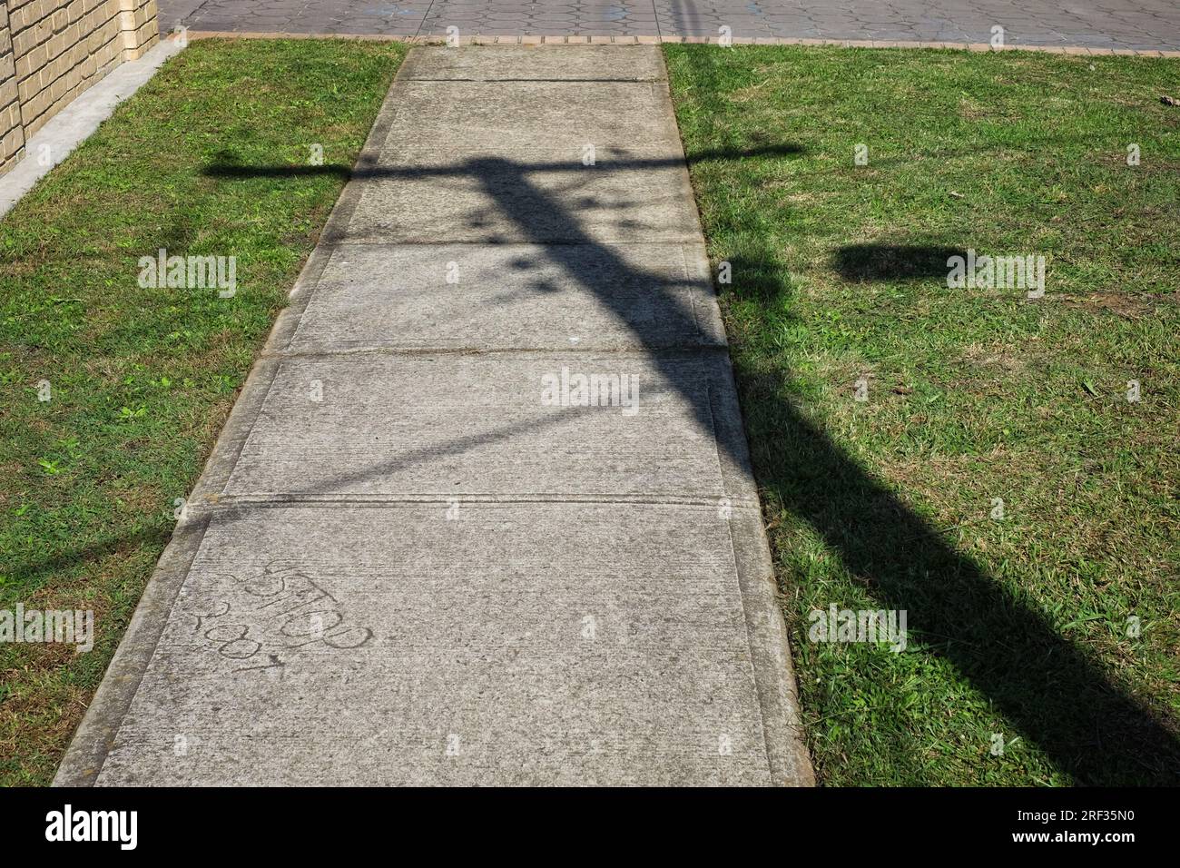Concrete footpath in Western Sydney with grass strips on either side ...