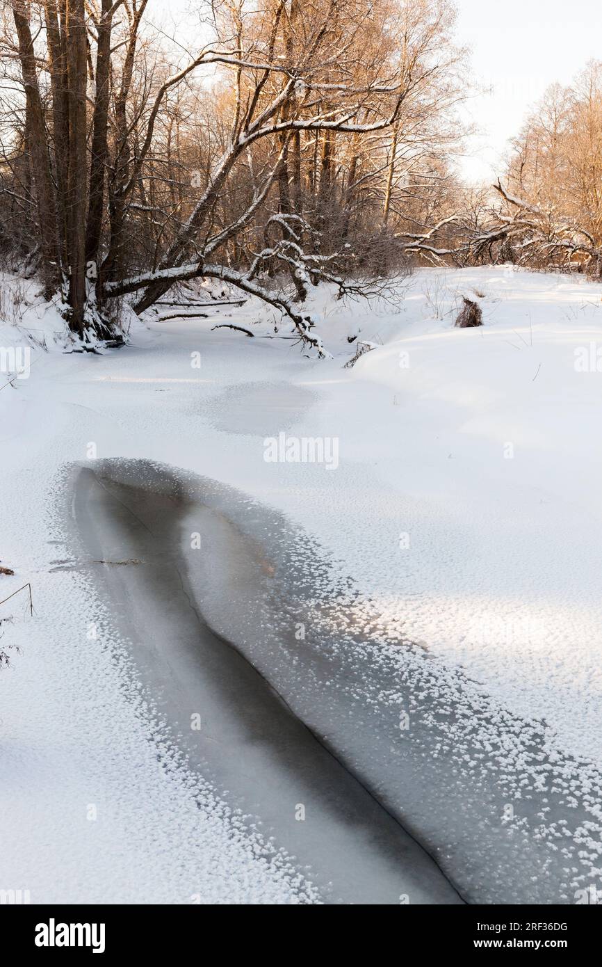 a small river whose water is frozen in winter, a frozen river during ...