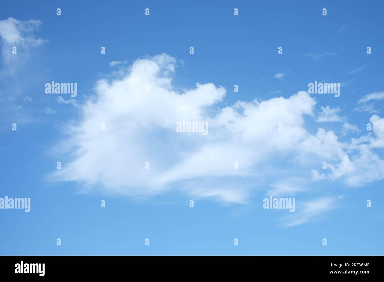 A soft and fluffy white cumulus cloud fills a crisp light blue sky of ...