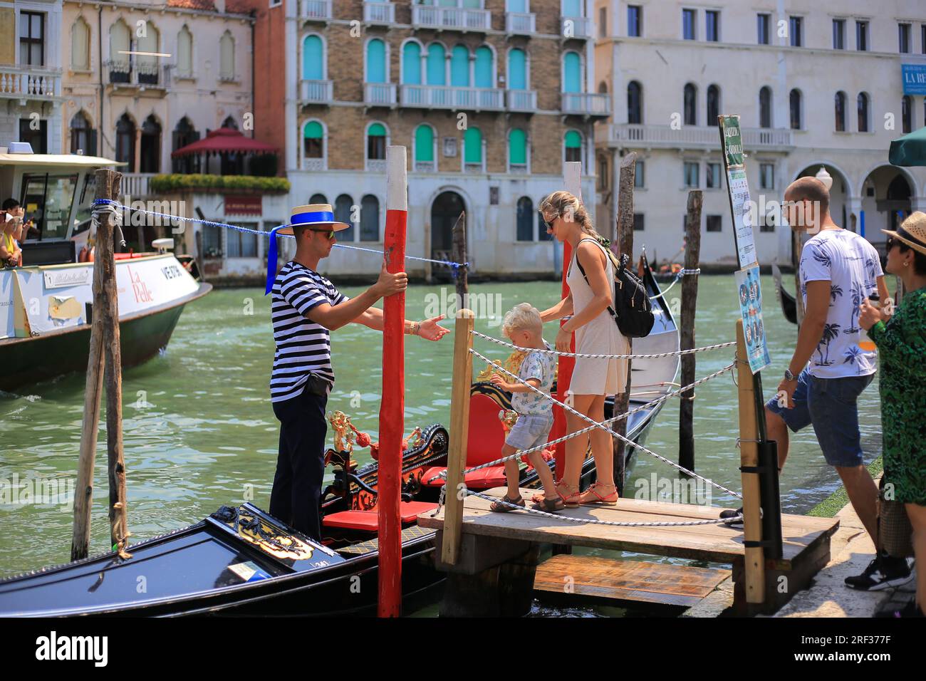 Gondolier invites passengers on board gondola in Venice Stock Photo - Alamy