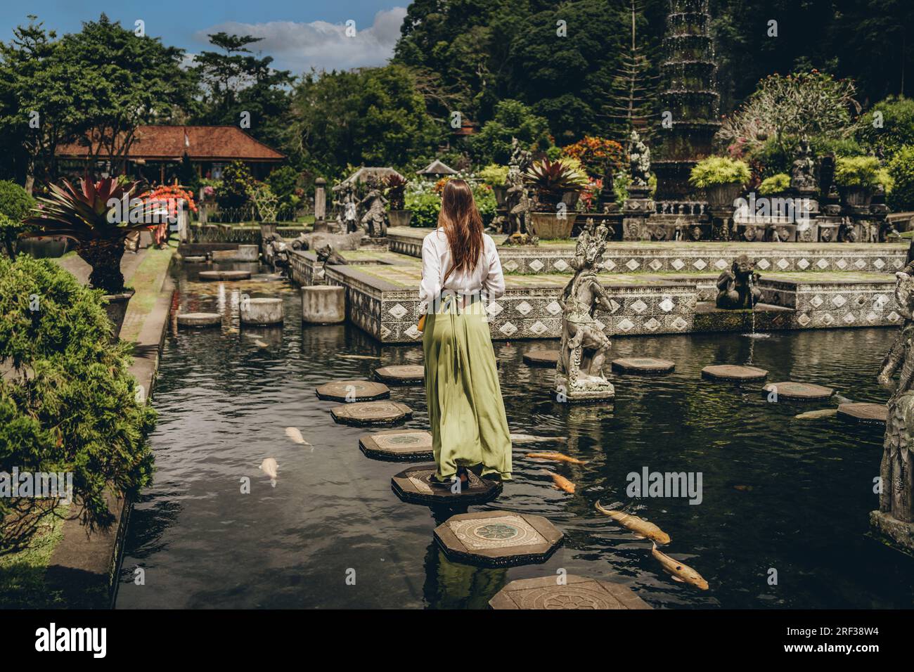 Girl walking in Saraswati temple water. Pura Taman Kemuda Saraswati ...