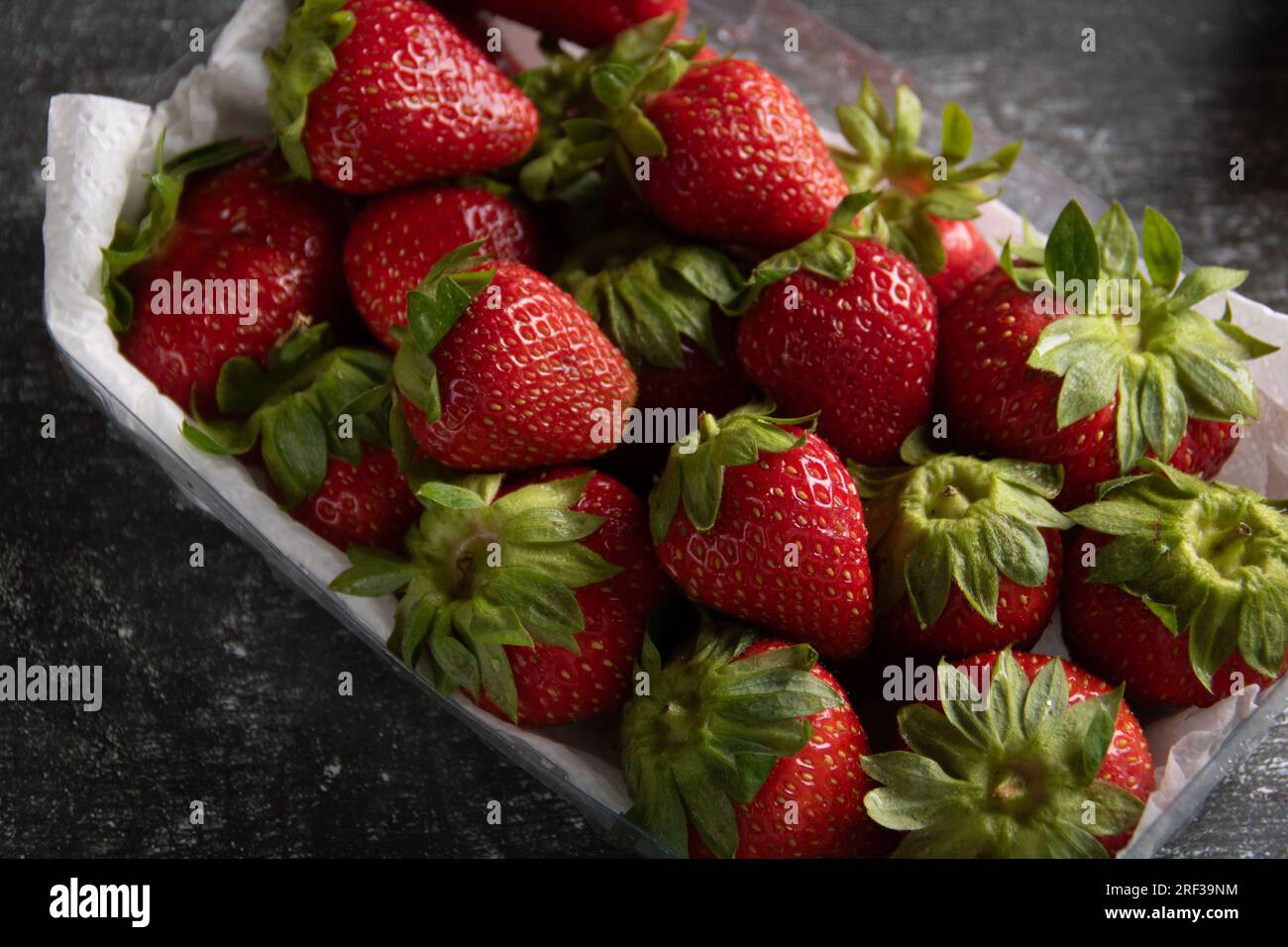 photo of many juicy, fresh, ripe strawberries in a plastic container, top view, vertical photo ...