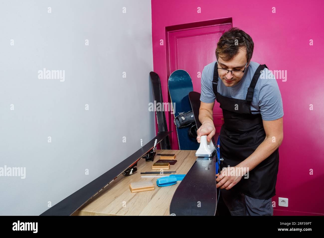 Ski repair guy hold iron wax waxing skis base Stock Photo - Alamy