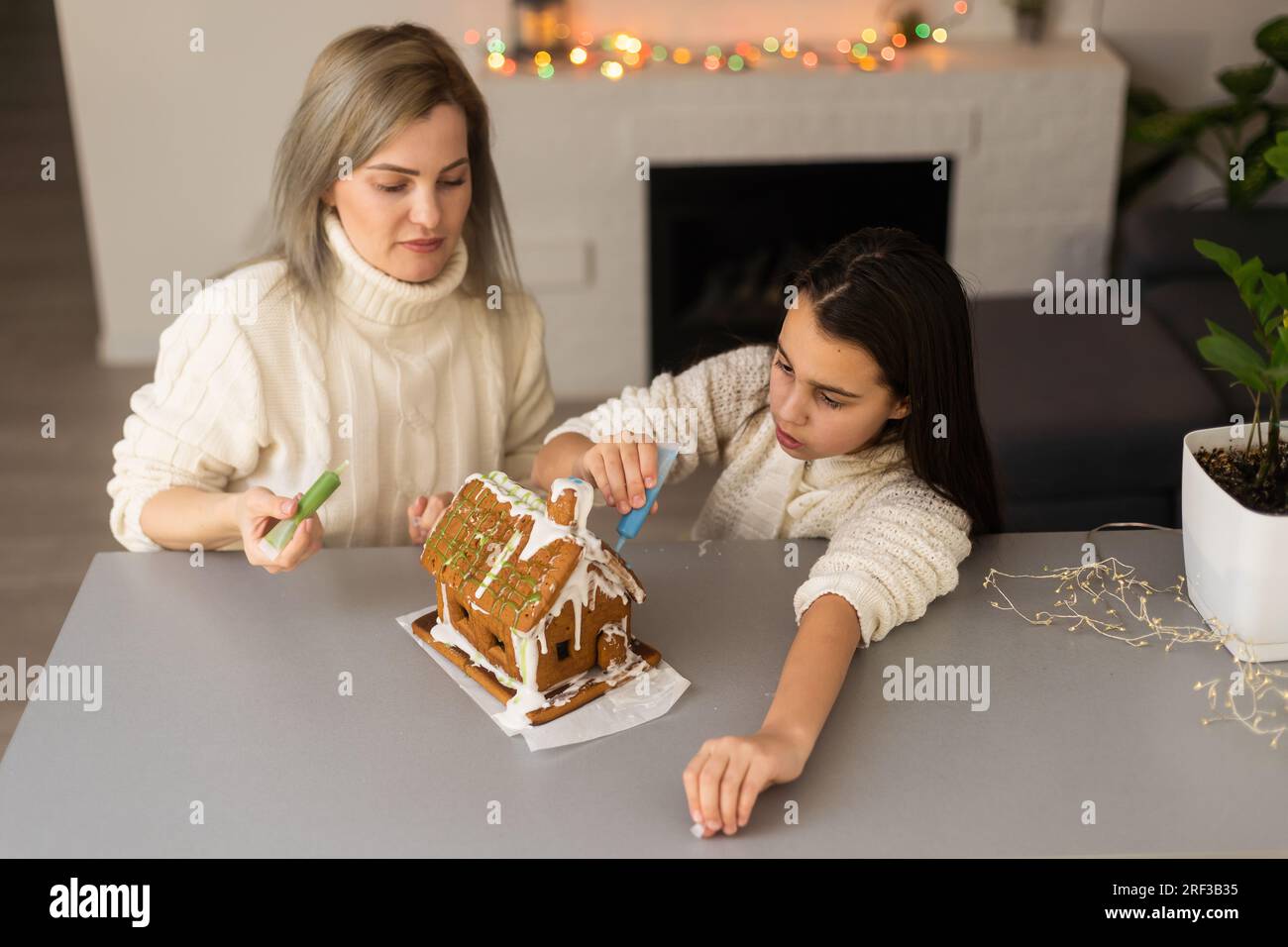 Family decorating gingerbread house on Christmas eve Stock Photo - Alamy