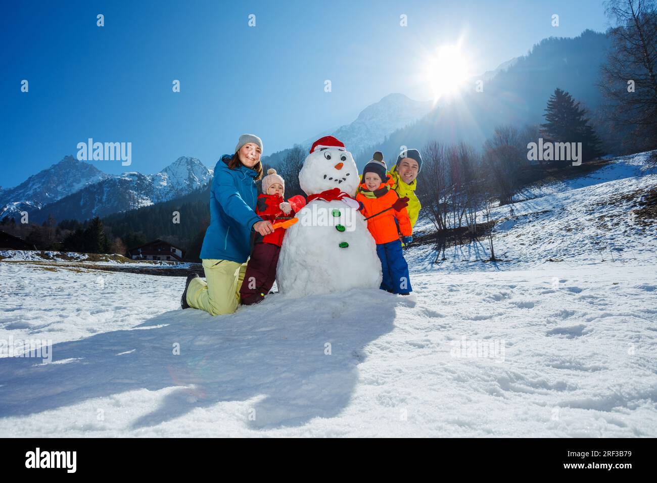 Father with mother and three kids play building snowman Stock Photo - Alamy