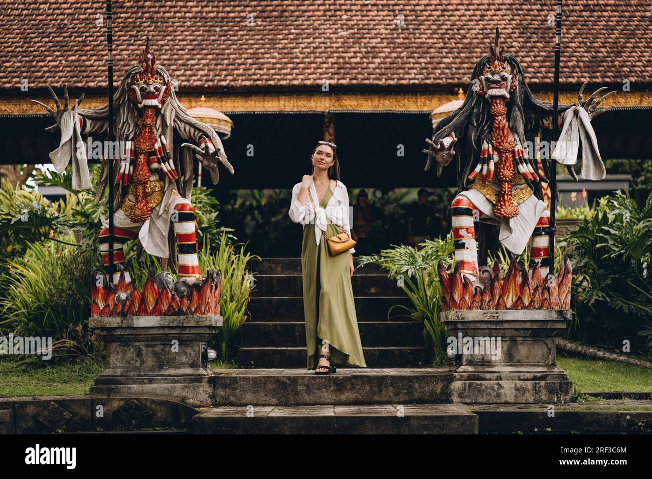 Beautiful girl between two statues with barong mask. Religious hindu ...