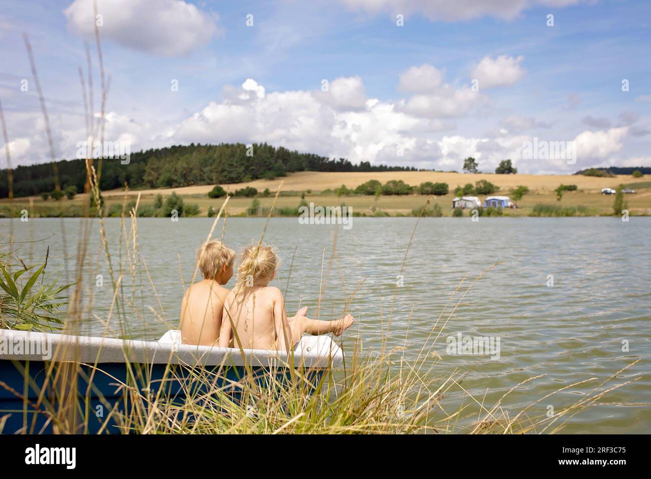 Beautiful blond children, boy and girl, siblings, sitting on a boat in ...