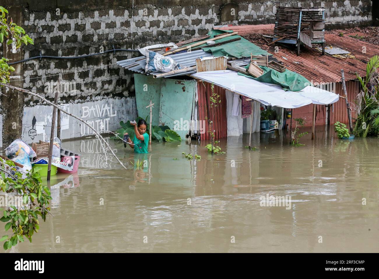 Bulacan Province. 31st July, 2023. A resident wades through floodwater ...