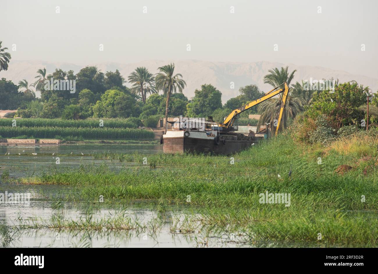 Panoramic landscape view across african river with large dredging barge ...
