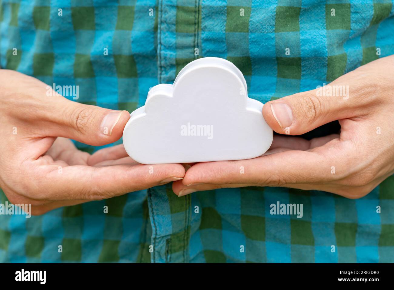 Man holding up a small white cloud object symbol in his hands, closeup. Cloud server computing ...