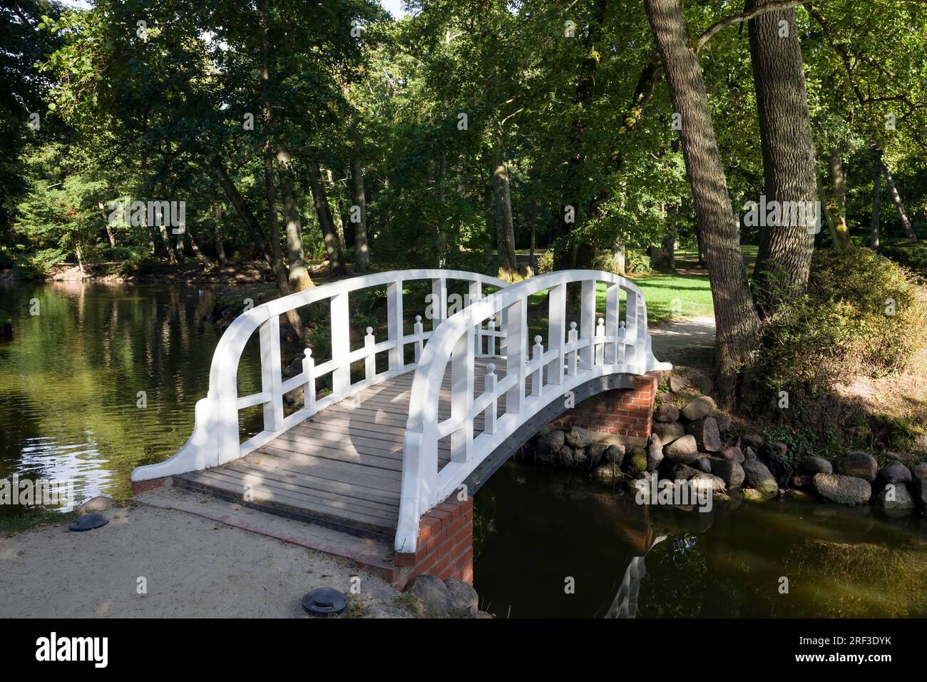 a simple white wooden bridge built across a narrow river for the ...