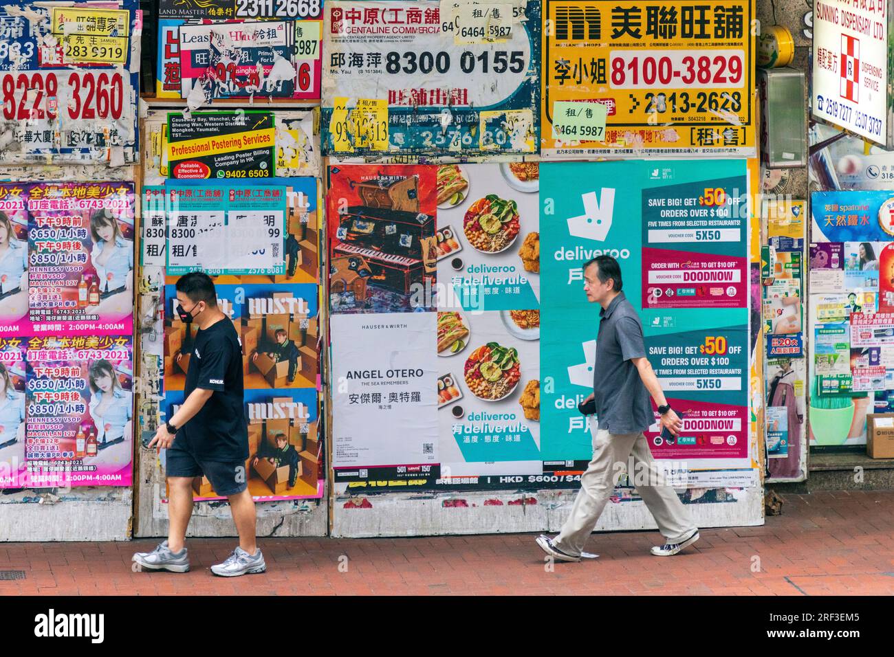 People walking past real estate and advertising posters on city centre ...