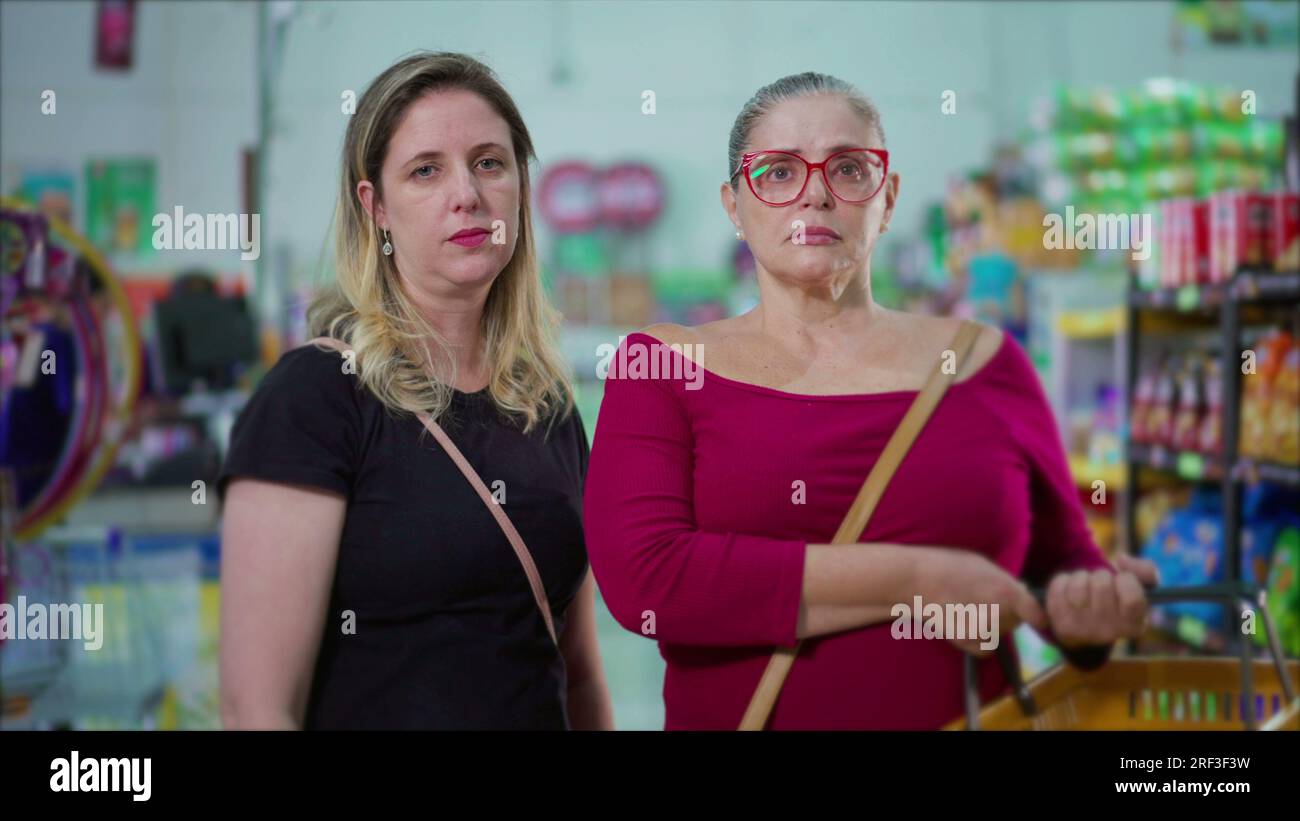 Stern Faced Middle-Aged Female Customers Holding Baskets Inside Grocery ...