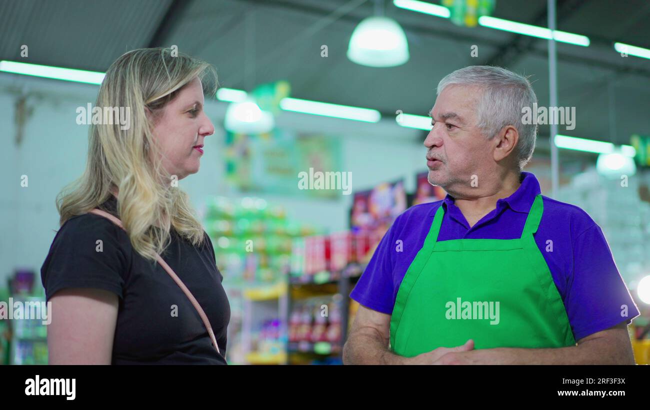 Senior employee of Grocery Store speaking with a female customer inside ...