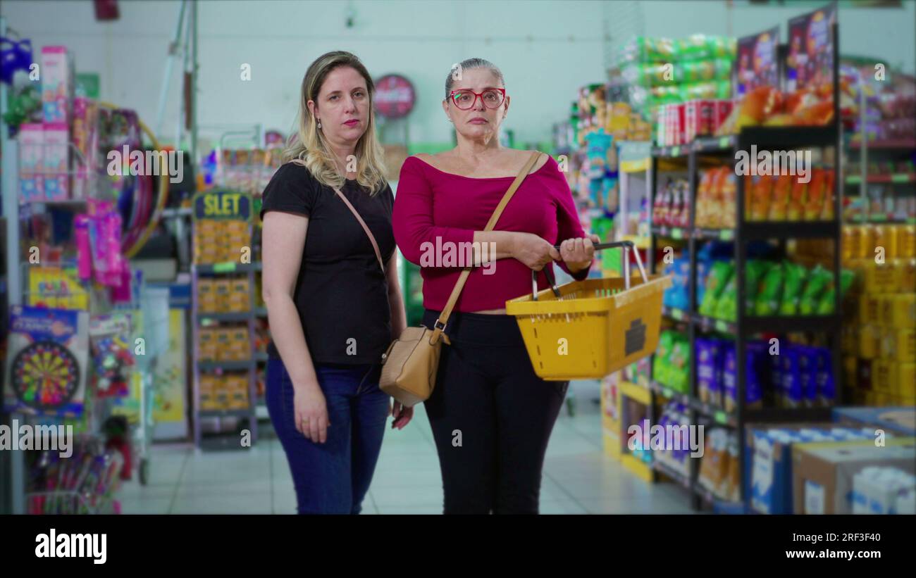 Stern Faced Middle-Aged Female Customers Holding Baskets Inside Grocery ...