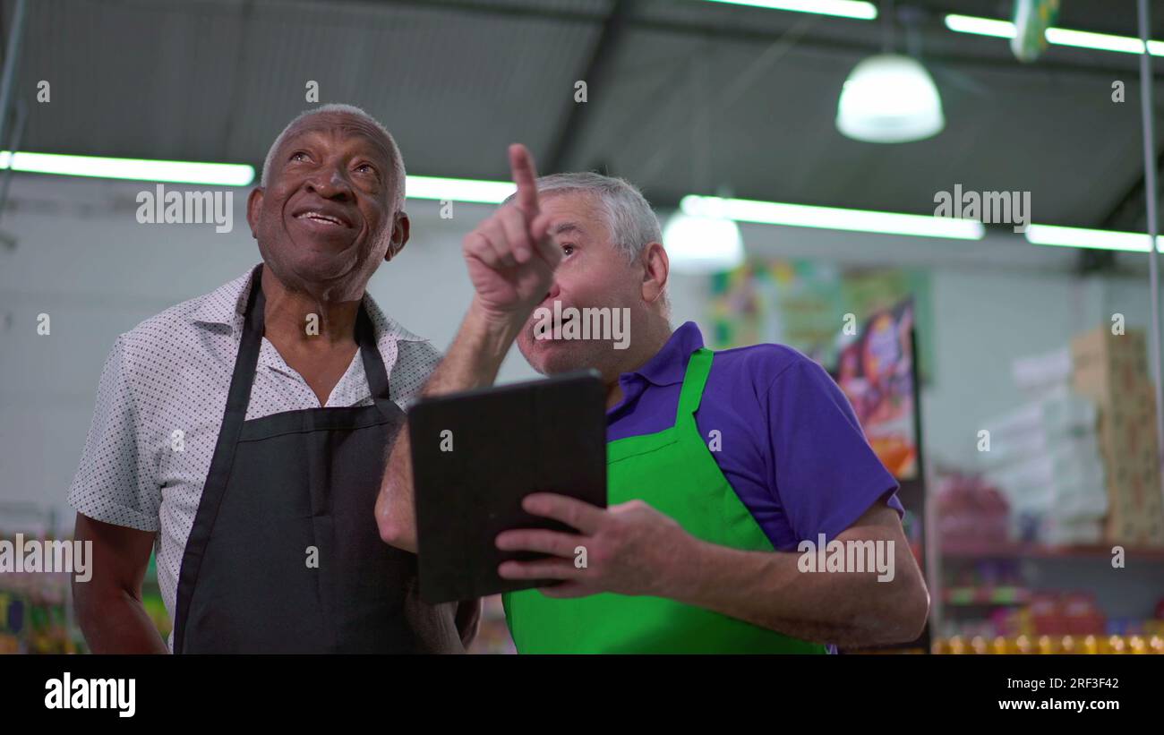Teamwork at Grocery Store, Older Manager Guiding Employee through ...