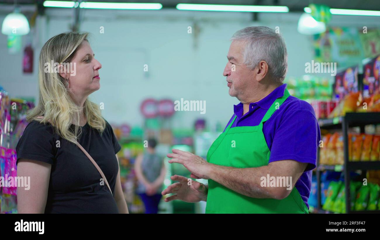 Senior employee of Grocery Store speaking with a female customer inside ...