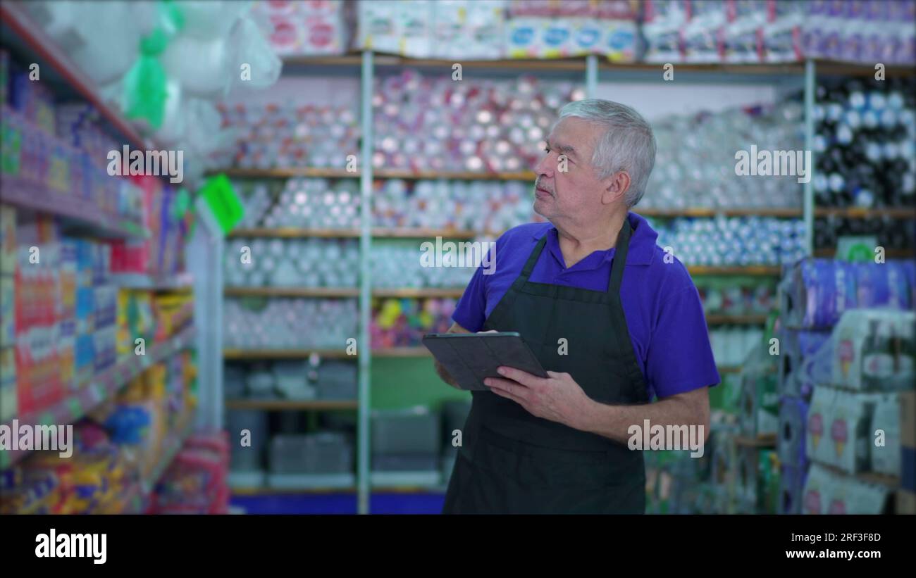 Senior manager of grocery store checking inventory of products on shelf ...
