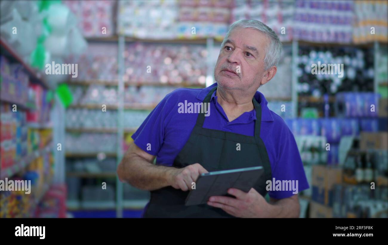 Senior manager of grocery store checking inventory of products on shelf ...