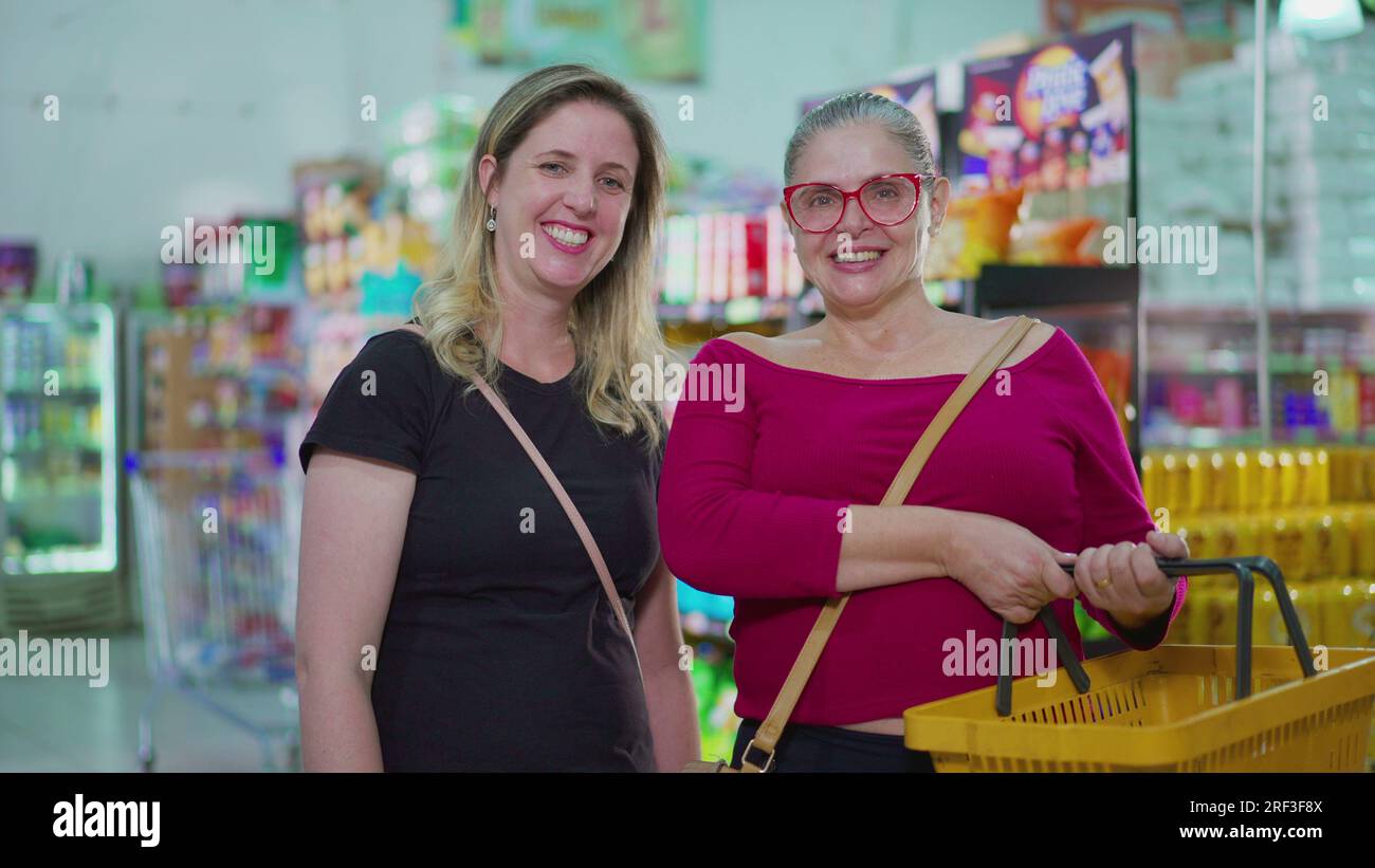 Two joyful female shoppers smiling at camera inside Supermarket store ...