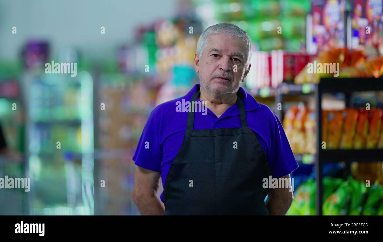 Serious concerned senior employee of supermarket standing inside ...