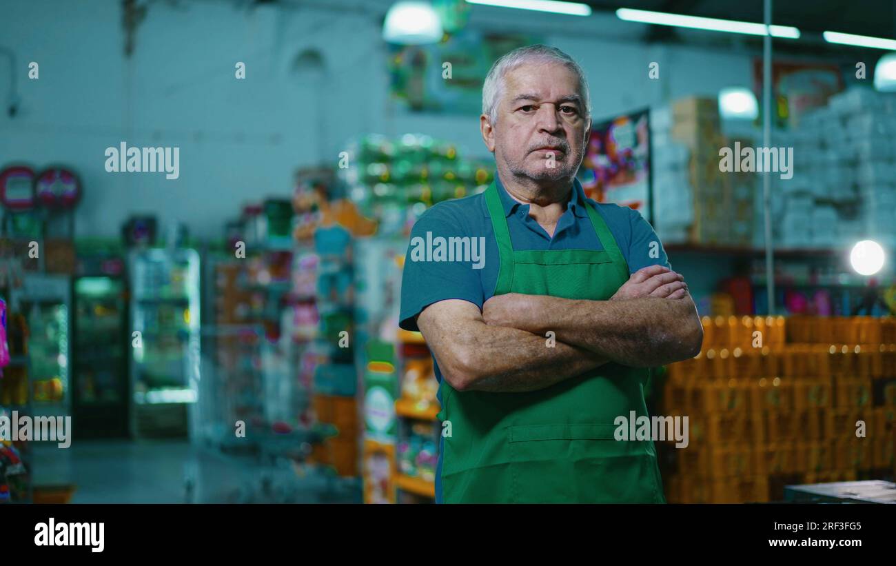 Serious small business owner with arms crossed standing inside Grocery ...