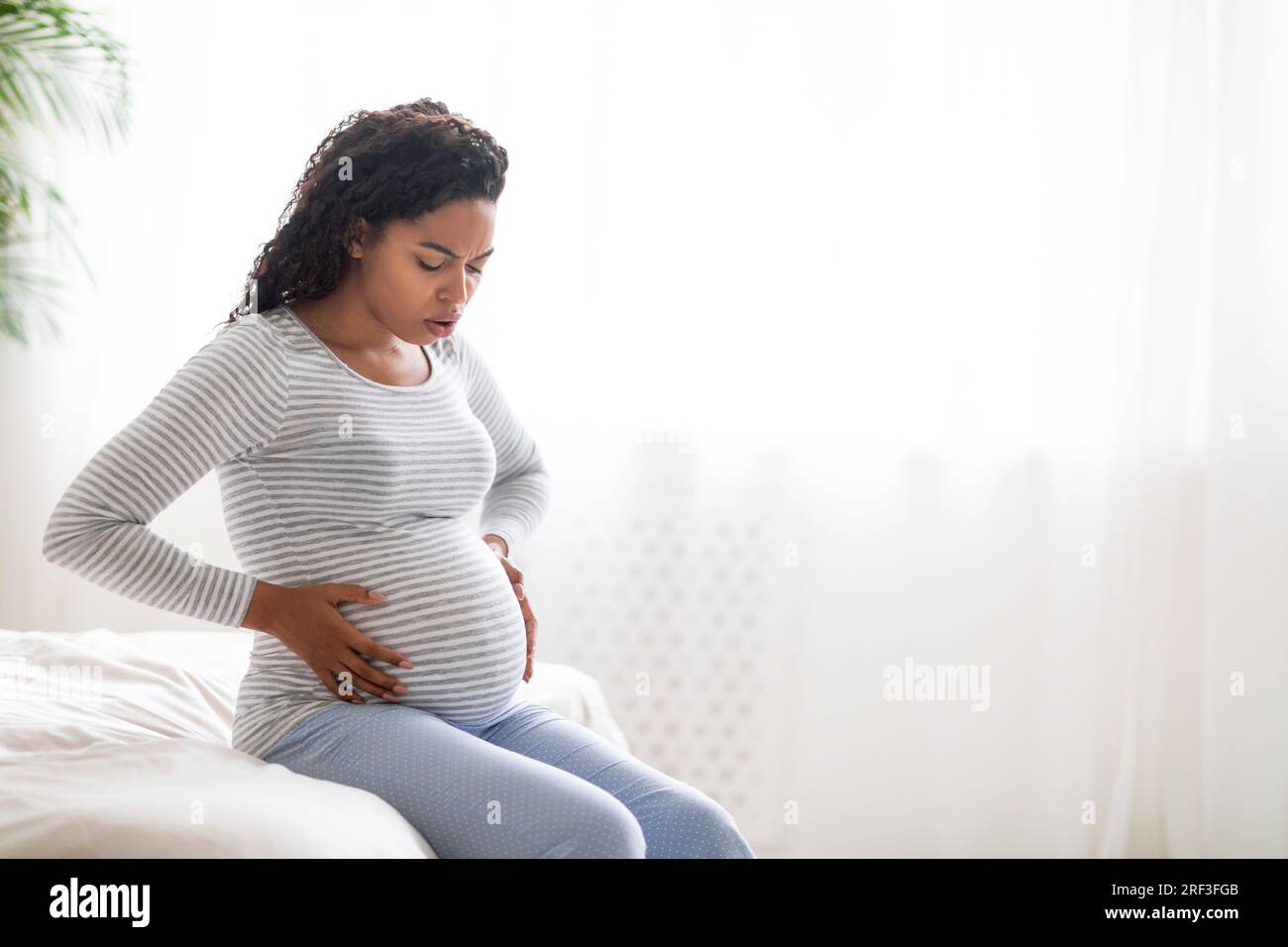 Braxton Hicks contractions. Young black pregnant woman suffering ...