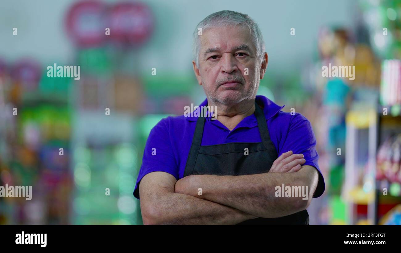 Serious older worker staff with arms crossed and stern expression ...