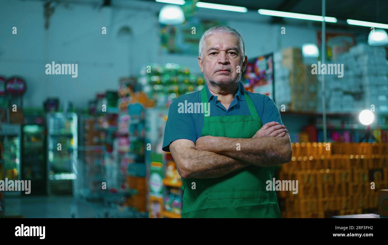 Serious small business owner with arms crossed standing inside Grocery ...