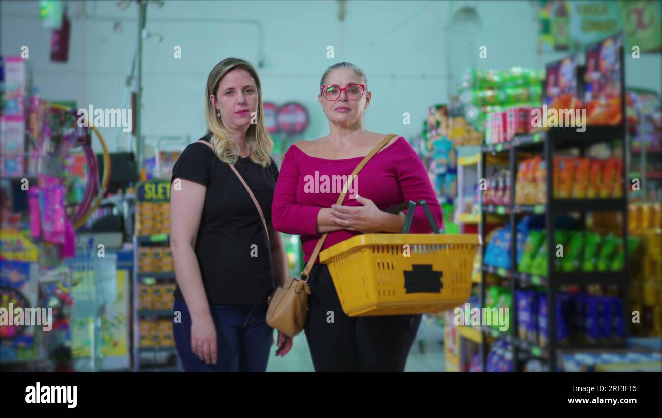 Portrait of two serious female customers standing inside grocery store ...