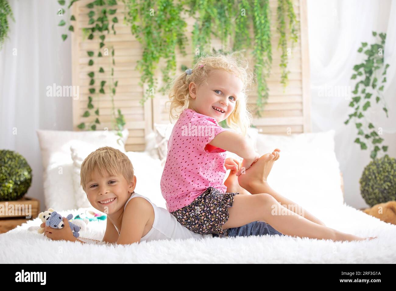 Cute sweet toddler children, tickling feet on the bed, laughing and ...